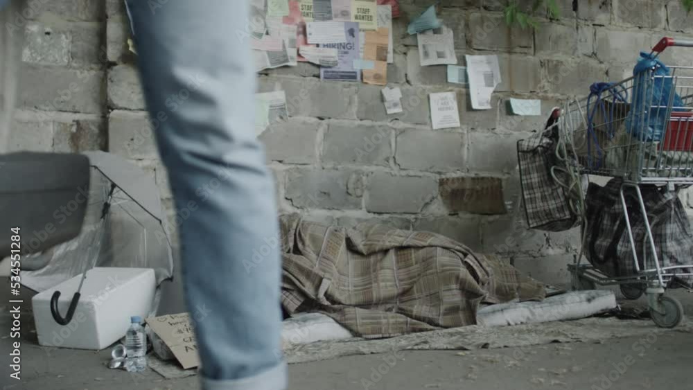 African American homeless man sleeping in rags on street while people ...