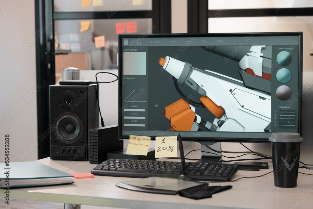 Designer's computer on a table with a 3D model of a dog robot on a monitor screen in a game and ...