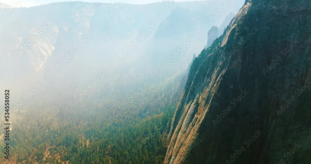 Wooded valley among the huge mountains covered with thick fog. Amazing ...