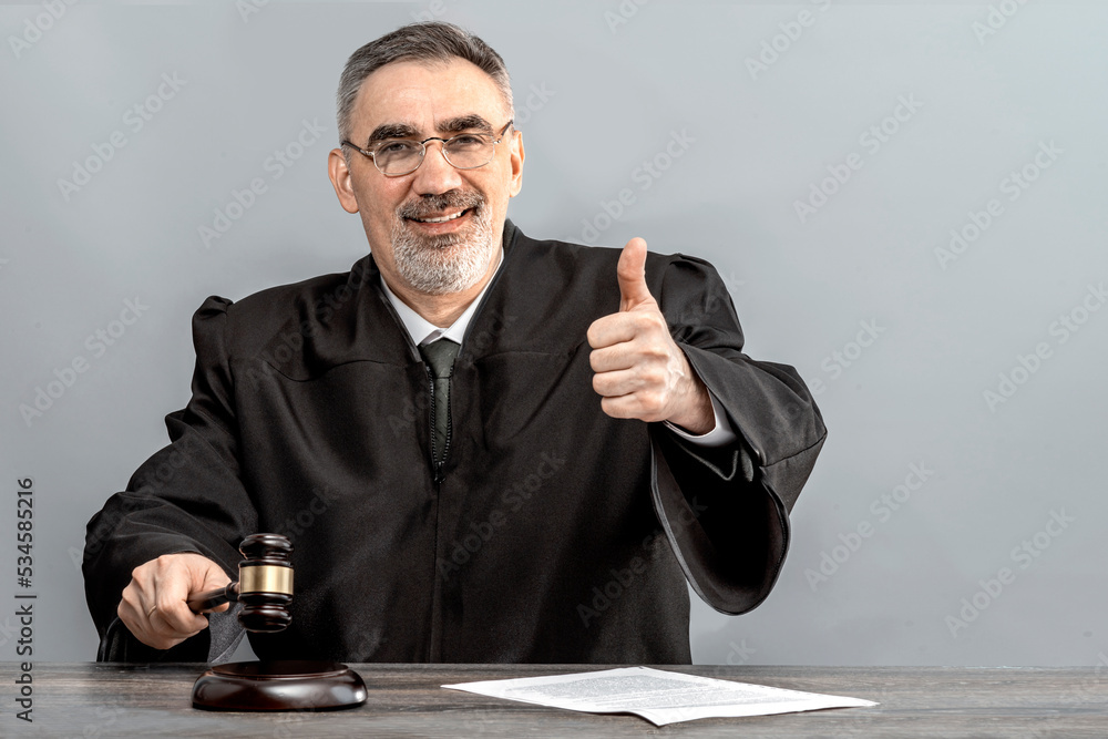 Judge showing thumbs up, judge's gavel on the table. Law Lord wearing ...