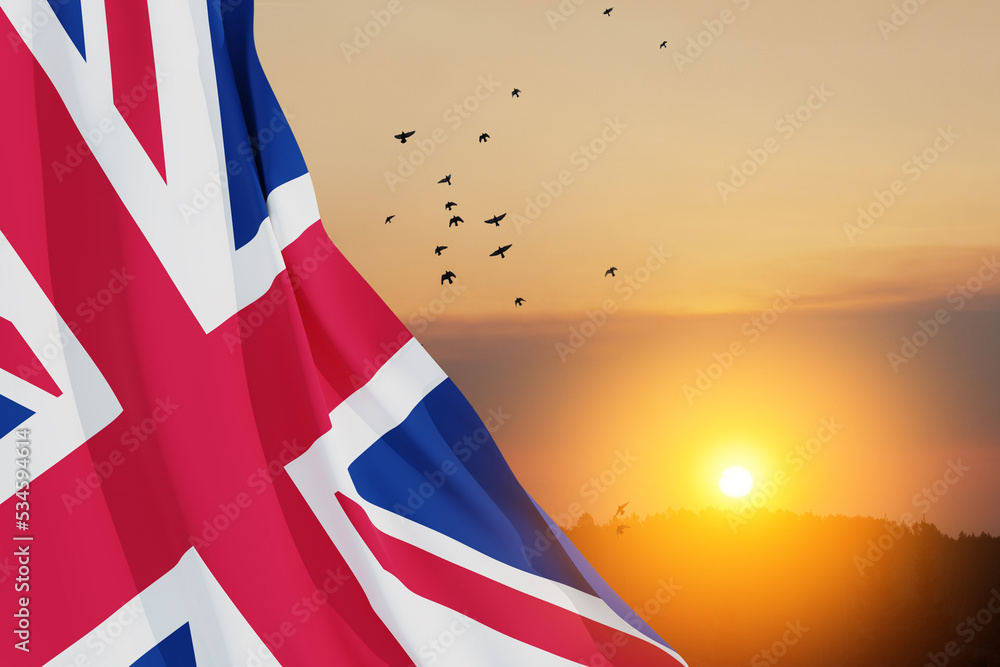 National flags of United Kingdom with flying birds on sunset sky ...