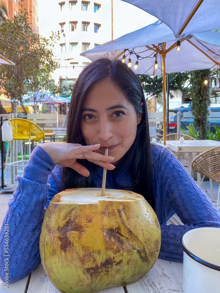 Mujer joven hispana tomando agua de coco de forma delicada en el ...