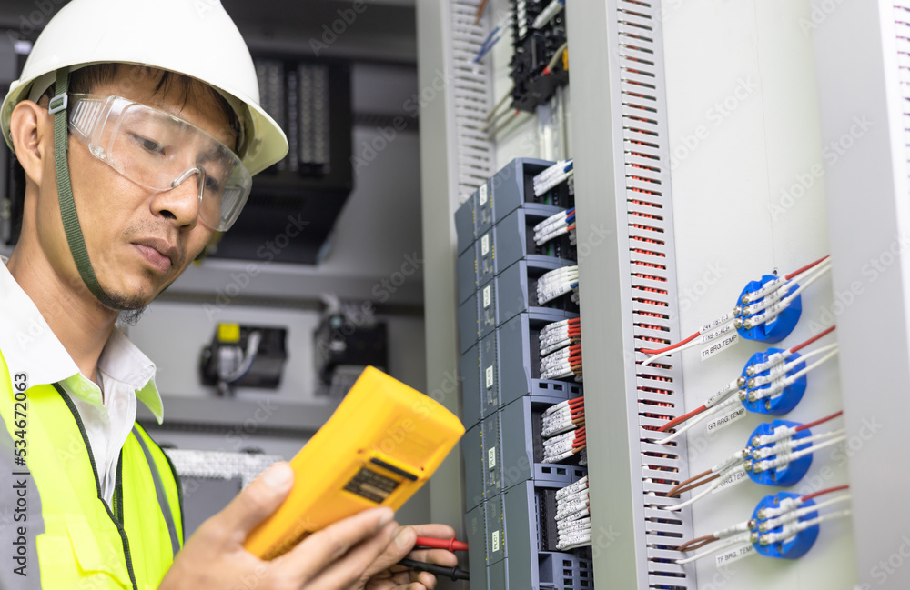 A male electrician works in a switchboard, Electrical terminal box ...