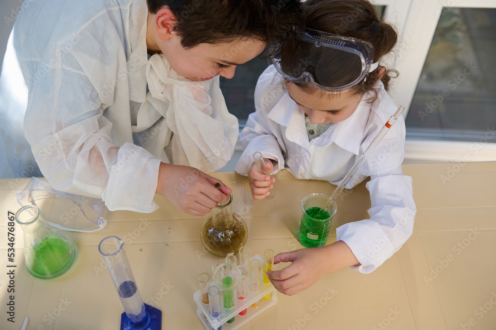 Overhead view of smart school kids, wearing white lab coat, learning ...