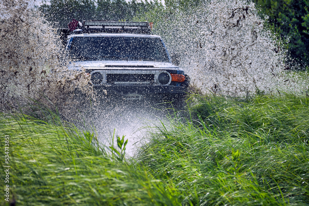 Water splashes during off-road racing. Blue SUV overcomes a dangerous ...
