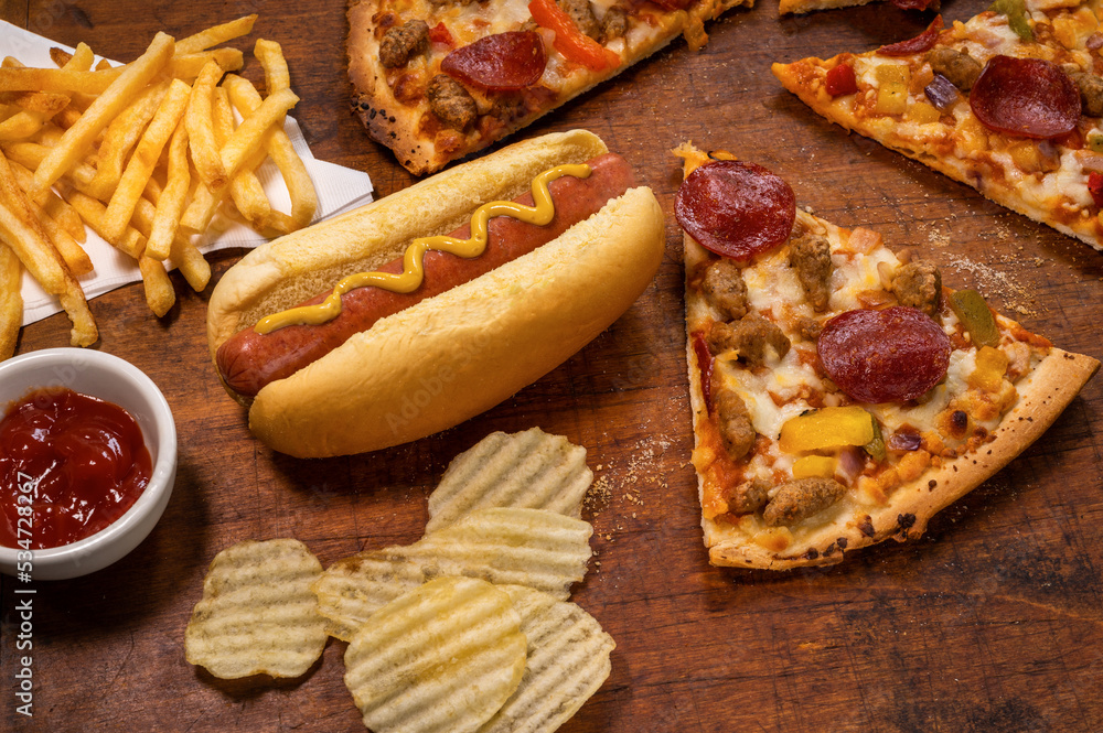 Variety of processed foods with pizza, hot dog, chips, and french fries ...