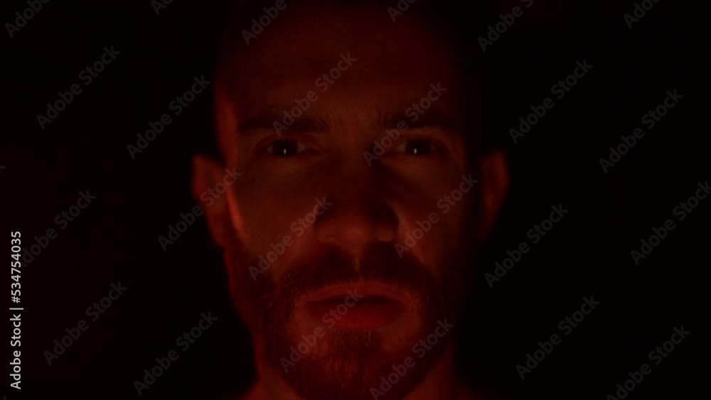 Angry man looking at camera with fury and rage, his face lit with fire ...