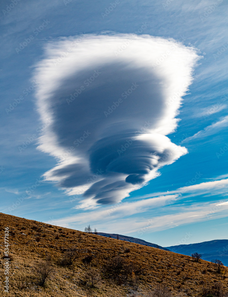 Strange shaped clouds in blue sky with sunlight above Dinaric Alps. Cloudy blue sky with white ...