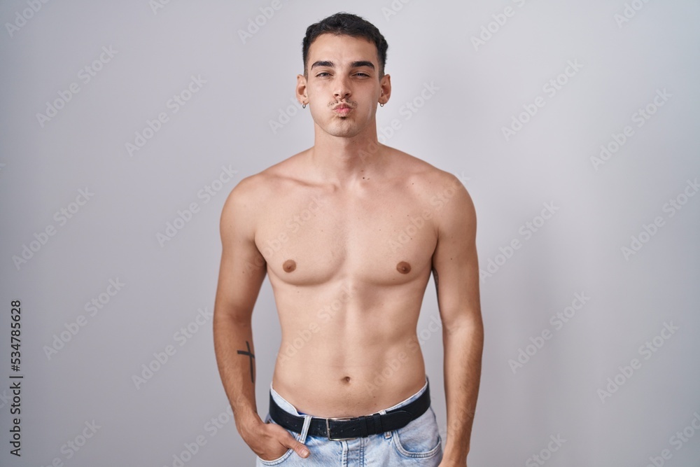 Handsome hispanic man standing shirtless puffing cheeks with funny face ...