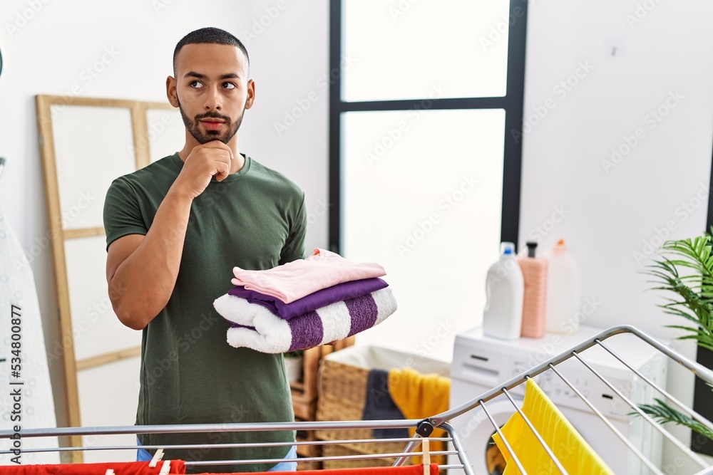 African american man holding folded laundry from clothline serious face ...