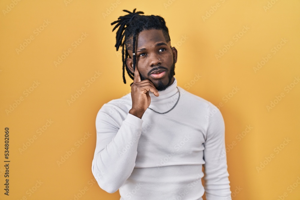 African man with dreadlocks wearing turtleneck sweater over yellow ...