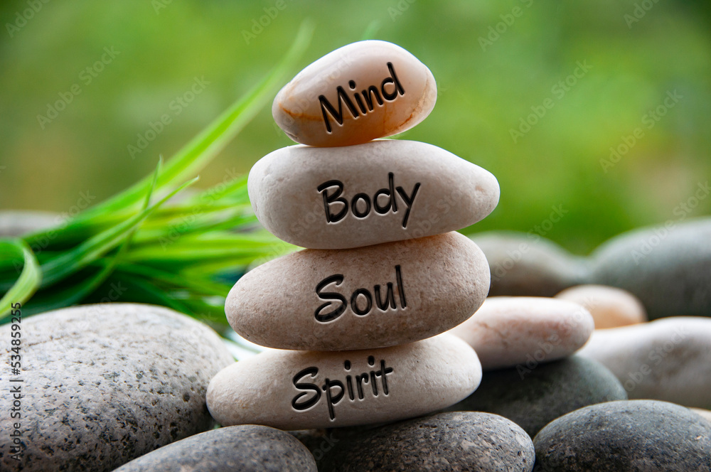Mind, Body, Soul and Spirit words engraved on zen stones with blurred nature background. Copy ...