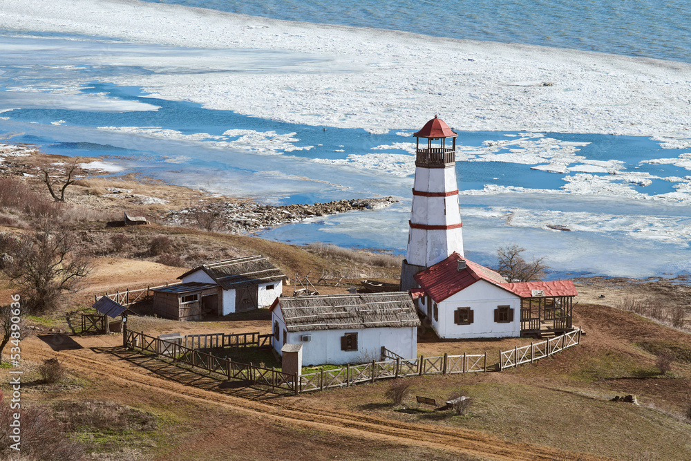 Beautiful white red lighthouse with farm utility houses in Merzhanovo ...