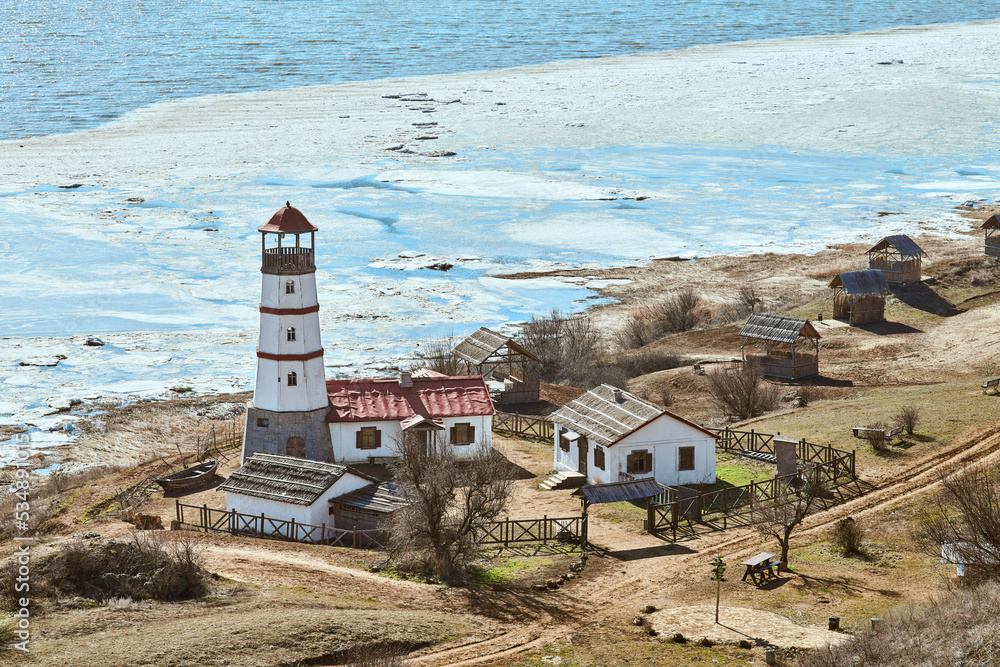 Beautiful white red lighthouse with farm utility houses in Merzhanovo ...