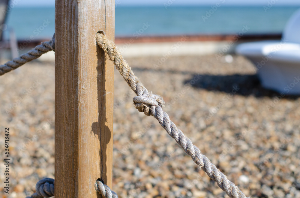 Wooden platform on the seashore. Fence made of old marine rope. Rope ...