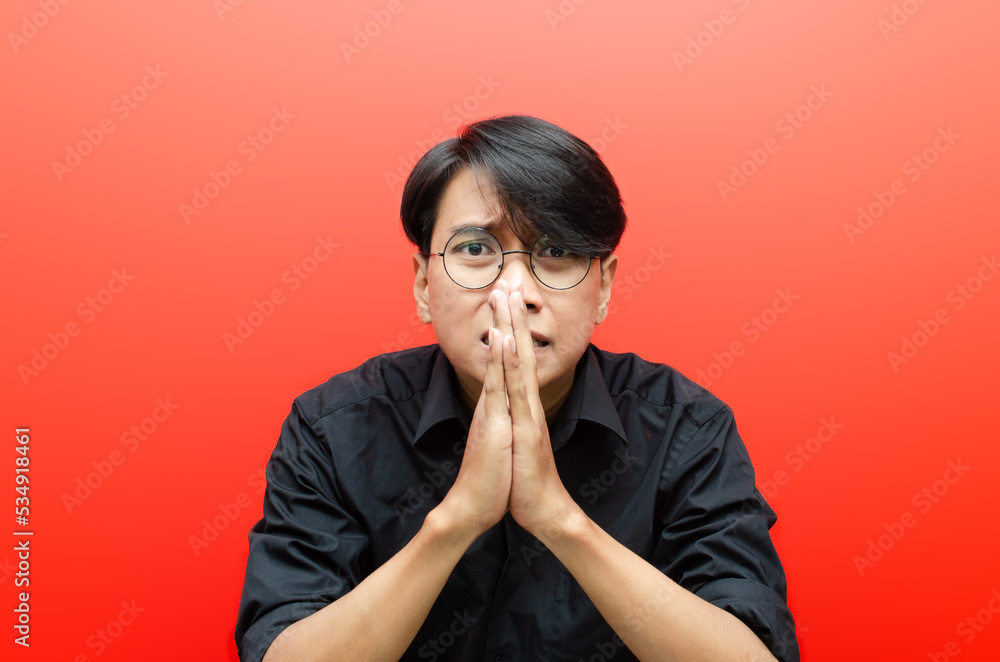 Sad young asian man begging frightenedly isolated over red background ...