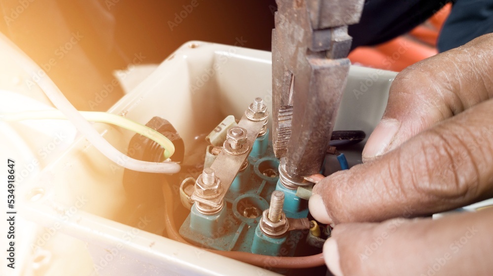 an Electrician Connecting the cable terminals power induction three ...
