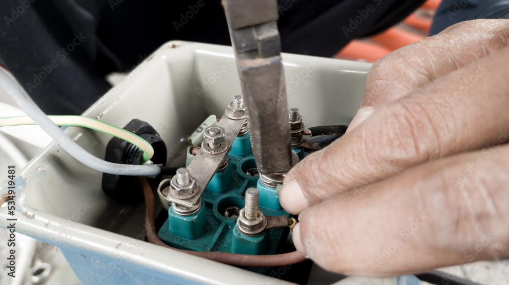 an Electrician Connecting the cable terminals power induction three ...