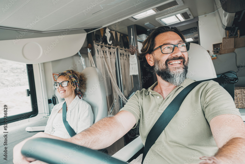 Inside view of happy adult couple driving and enjoying road trip in a ...