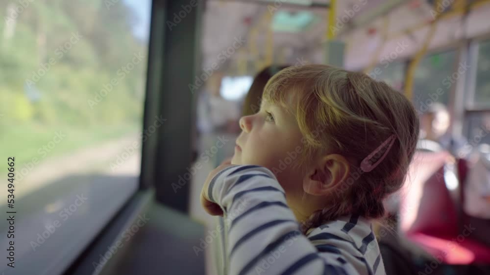 Little blonde girl enjoys the scenery from the bus window. The kid ...