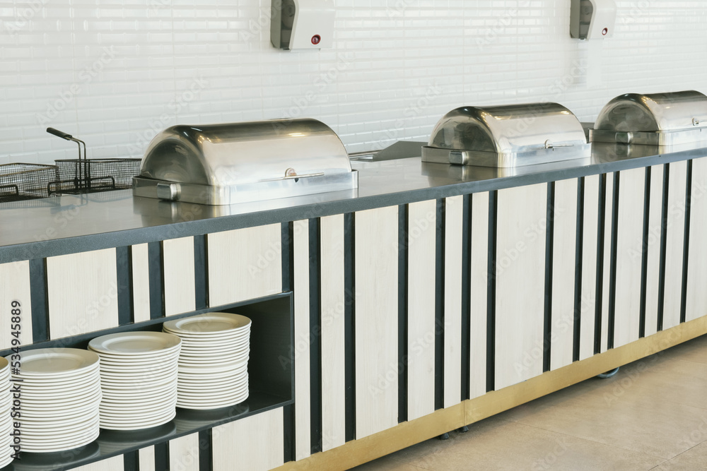 Foto de Buffet counter with plates and metal containers for hot dishes ...