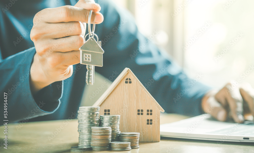 Men holding house model in hand and calculating financial chart for ...