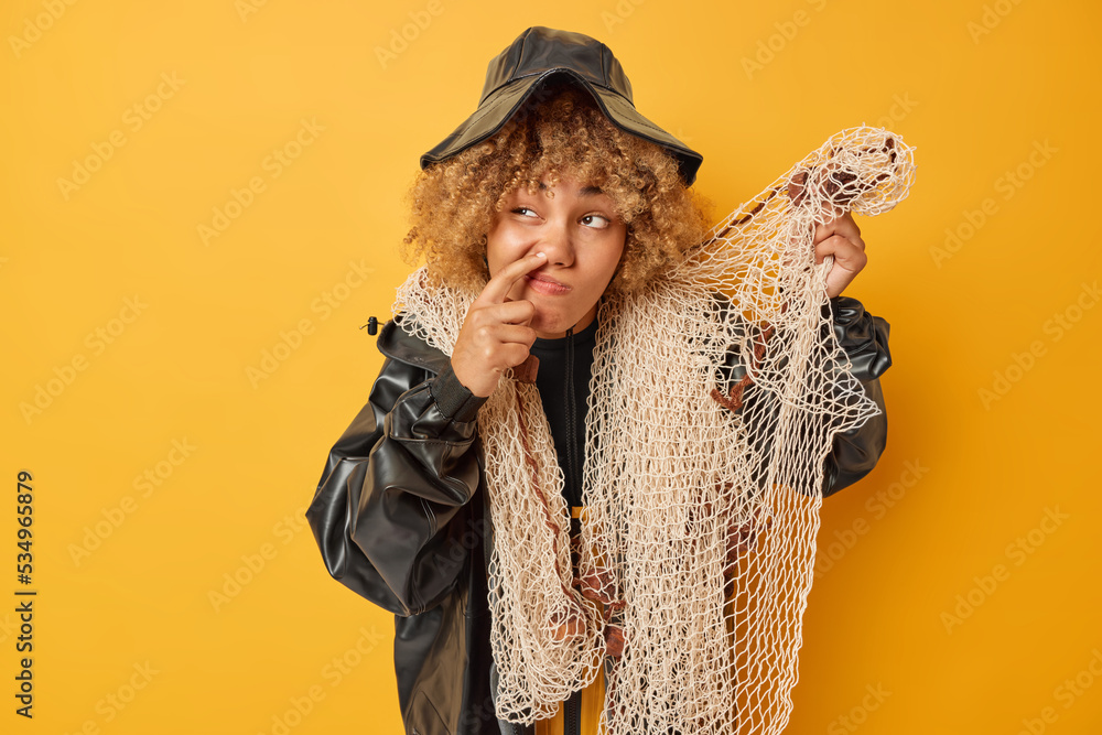 Bored thoughtful curly haired fisherwoman keeps finger in nostril ...