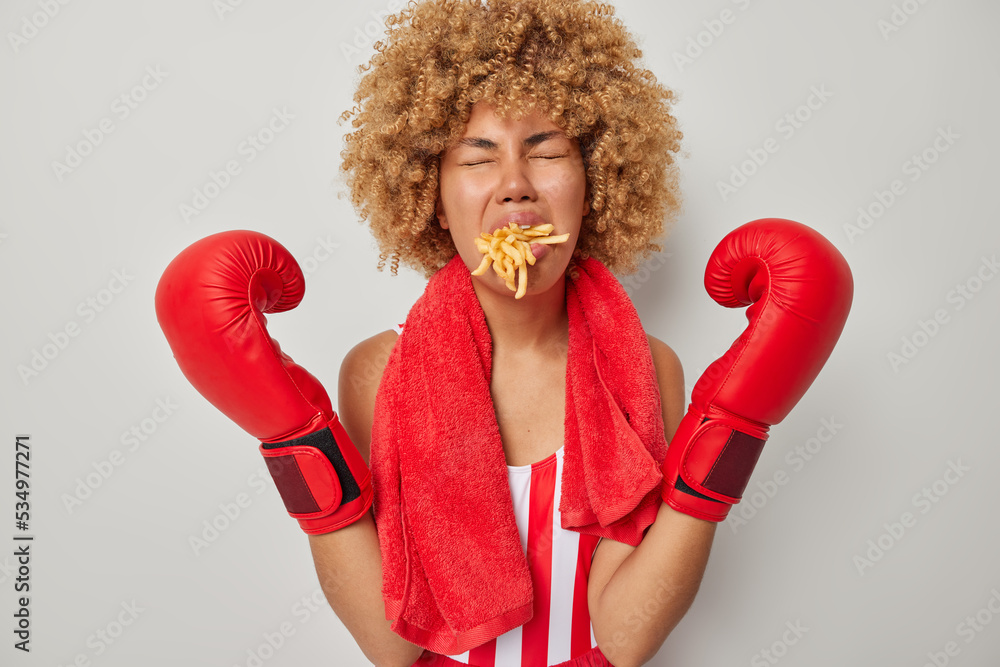 Frustrated upset woman with curly hair has mouth full of french fries ...