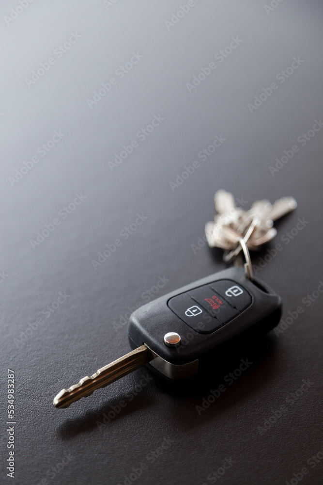 Car key on top of a black table with natural light. Key with buttons to ...