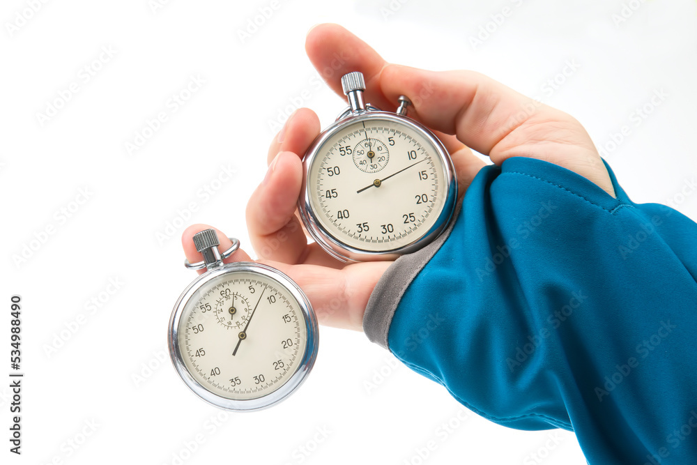 Two mechanical stopwatches hang on the fingers of a male hand. Time ...
