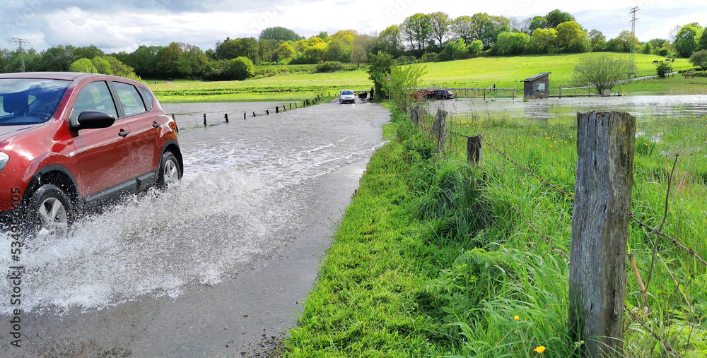 Car driving through deep water puddle on flooded road in Danish ...