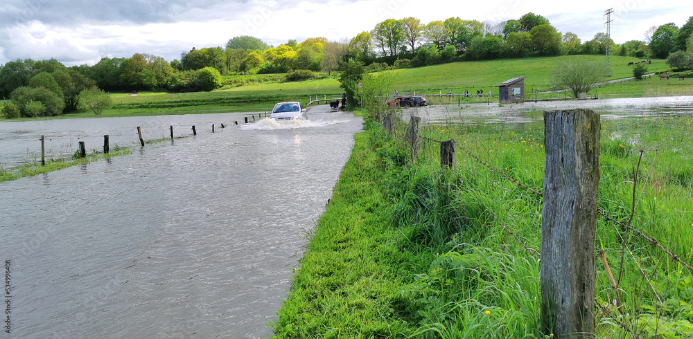 Car driving through deep water puddle on flooded road in Danish ...