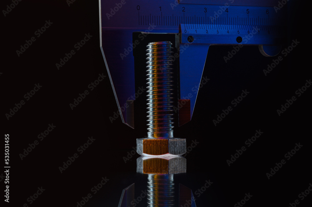 metal, chrome-plated nuts of different sizes and a caliper measuring ...