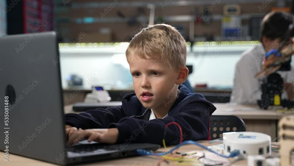 Portrait of smart cute little boy programming software for robotics at ...