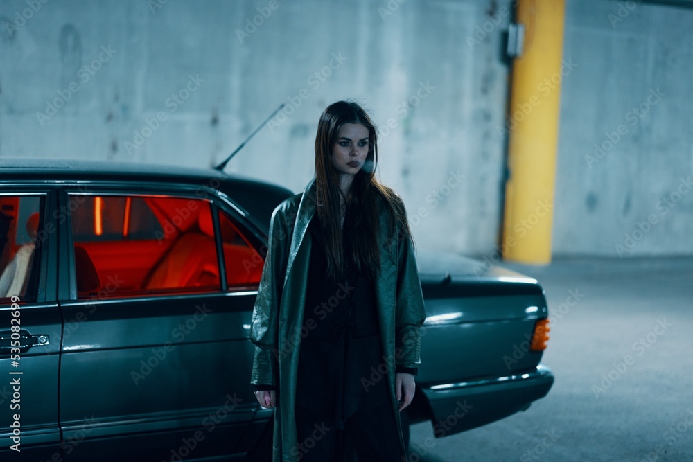 a stylish woman is standing in a long leather coat next to a vintage ...