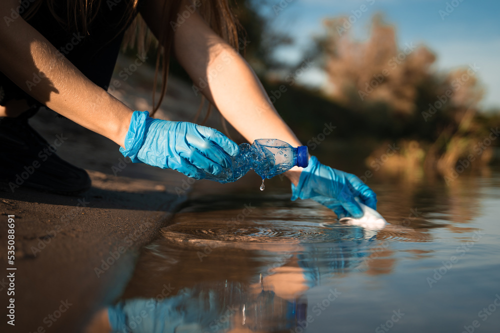 Hands collecting garbage and garbage from river, sea water, collecting ...