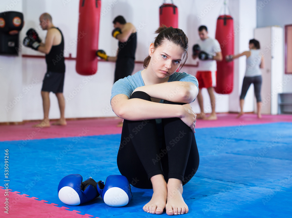 Defeated young girl sitting on the floor in the boxing hall Stock Photo ...