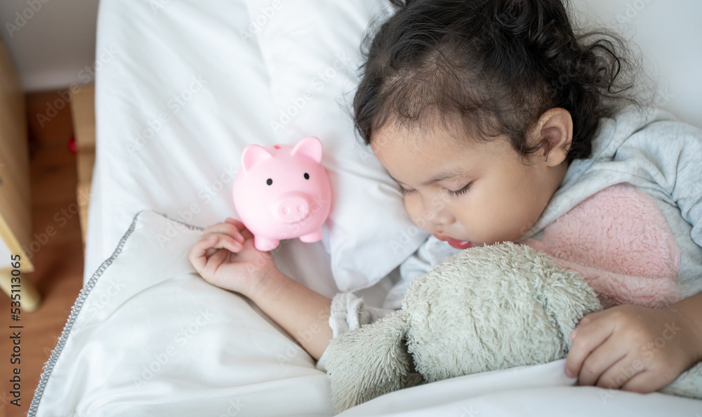 Caucasian Cute female child sleeping on a piggybank on bedroom.Baby ...