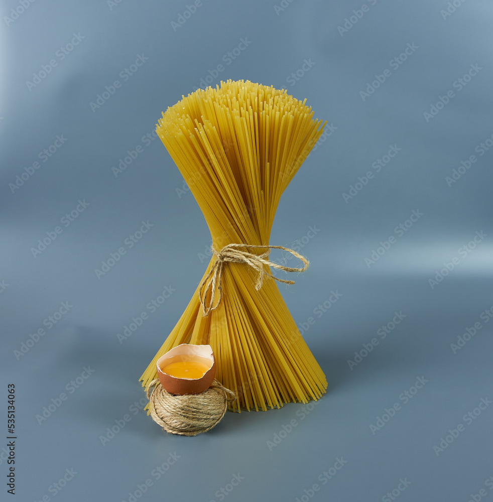 Spaghetti pasta bunch close-up on gray background with half a chicken ...