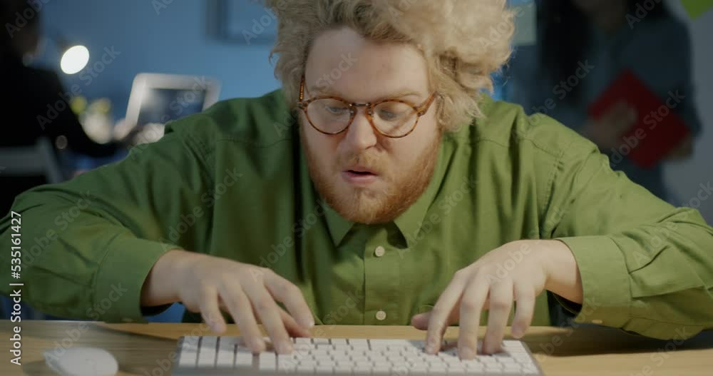 Portrait of comic guy working with computer typing in rush looking at ...