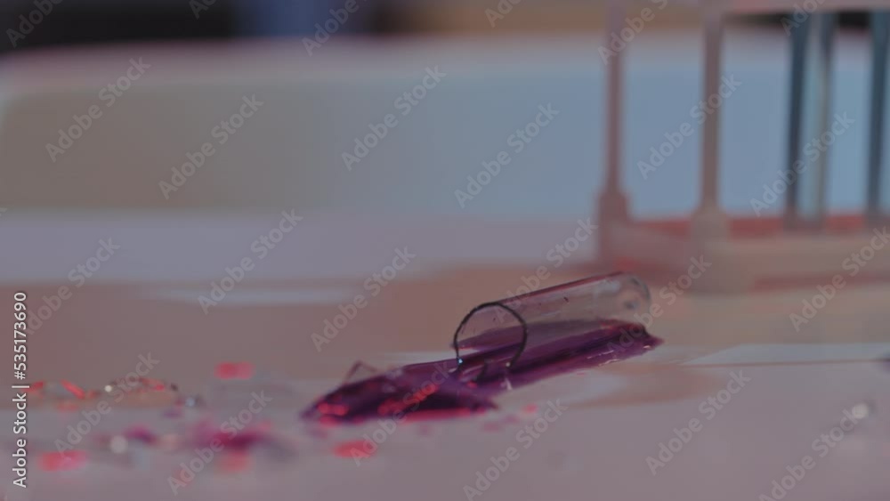 Close-up of broken test tube with hazardous liquid on desk in ...