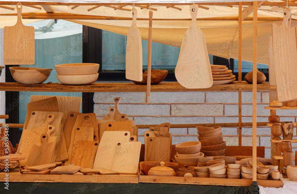 Stand at a street market selling wooden kitchen accessories as bowls, dishes and cutting boards ...