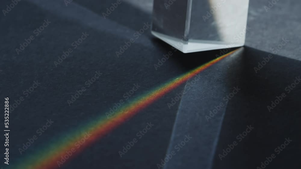 Close up tilt up shot of glass prism being moved and dispersing light ...