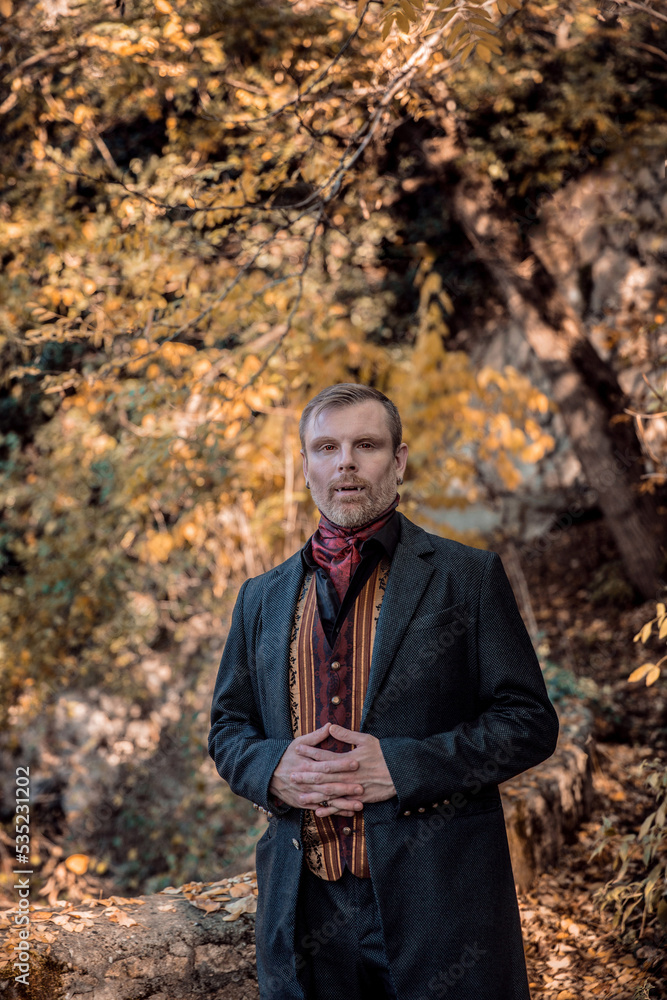 Vampire man wearing victorian suit in the autumn forest. Vintage ...