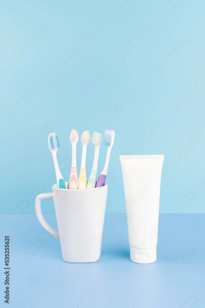 Toothbrushes in a glass and toothpaste tube with empty label on light ...