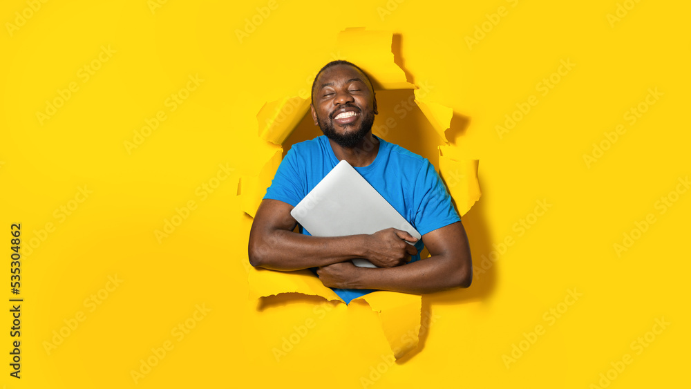 Gadget lover. Happy black man hugging laptop computer and smiling ...