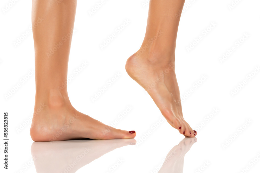 Side view of a beautifully cared female feet on a white background ...