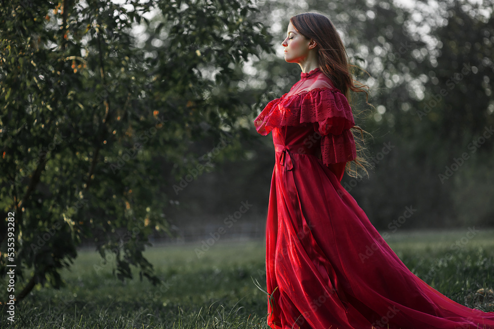Mature woman in red dress standing in the woods Stock Photo | Adobe Stock
