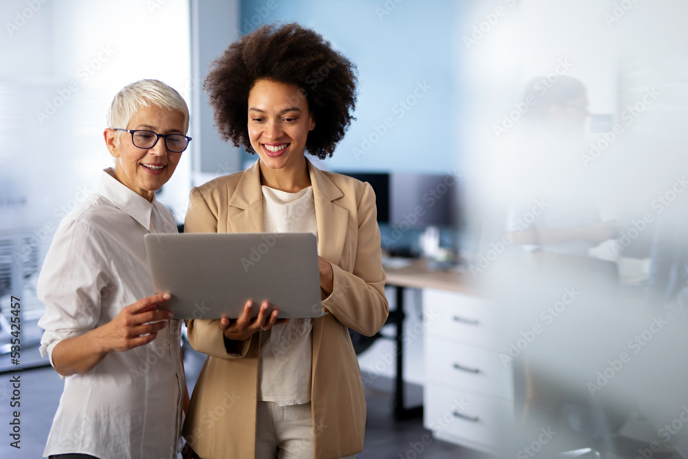 Happy multiethnic business women working together online on a laptop in corporate office. Stock ...