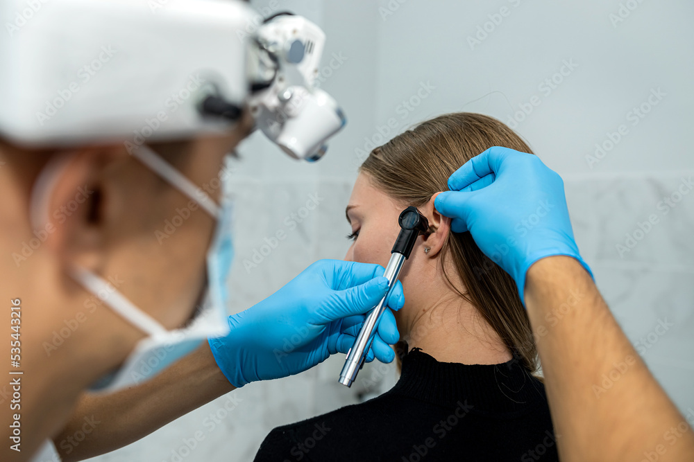 male doctor or ENT specialist examining the ear with an endoscope with ...